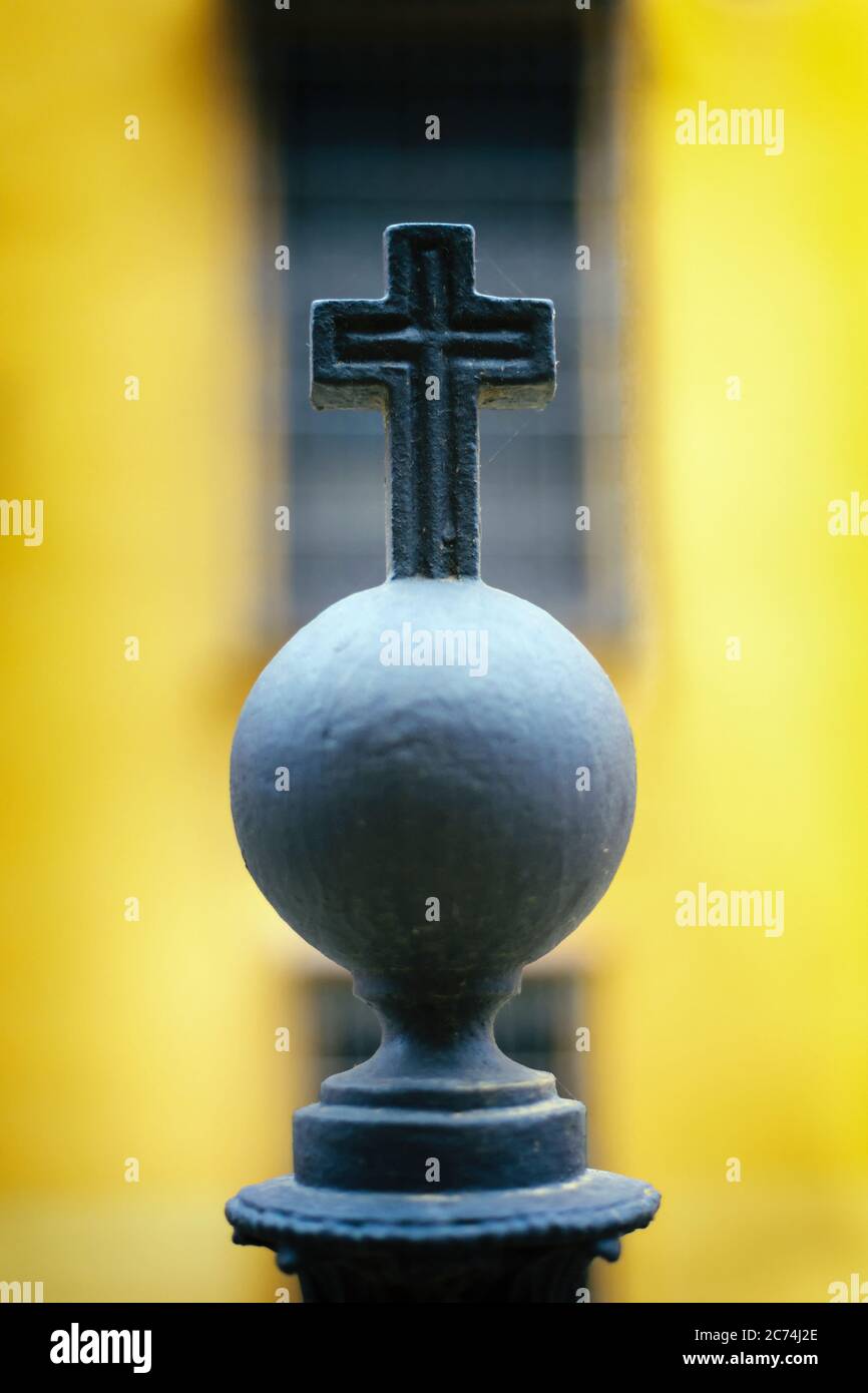 Crucifix on ball. Part of decoration on wrought iron fence surrounding ...