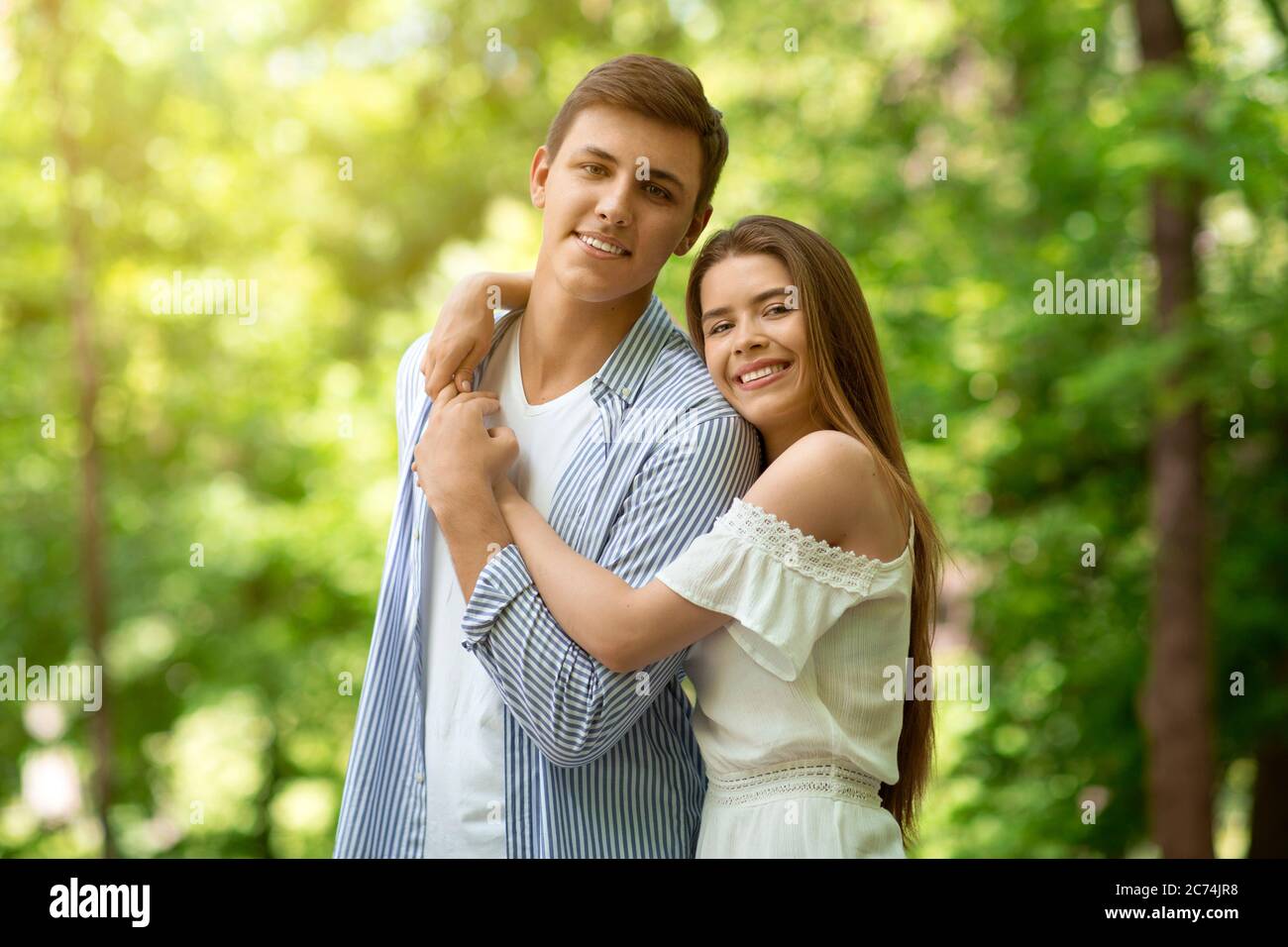 Affectionate girl hugging her boyfriend at park in summertime Stock Photo - Alamy