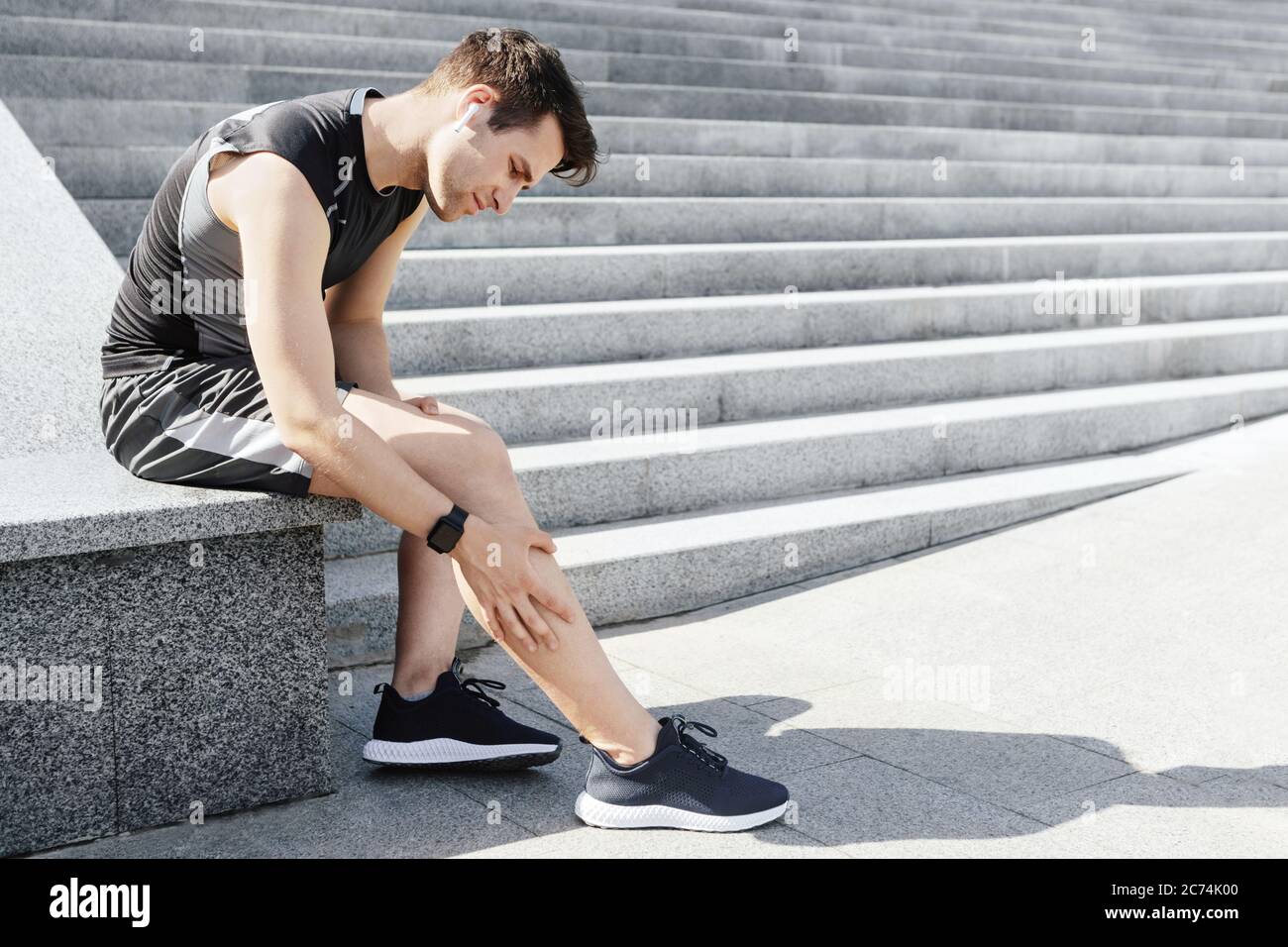 Leg injury. Guy with expression of pain on face, sits and rubs leg ...