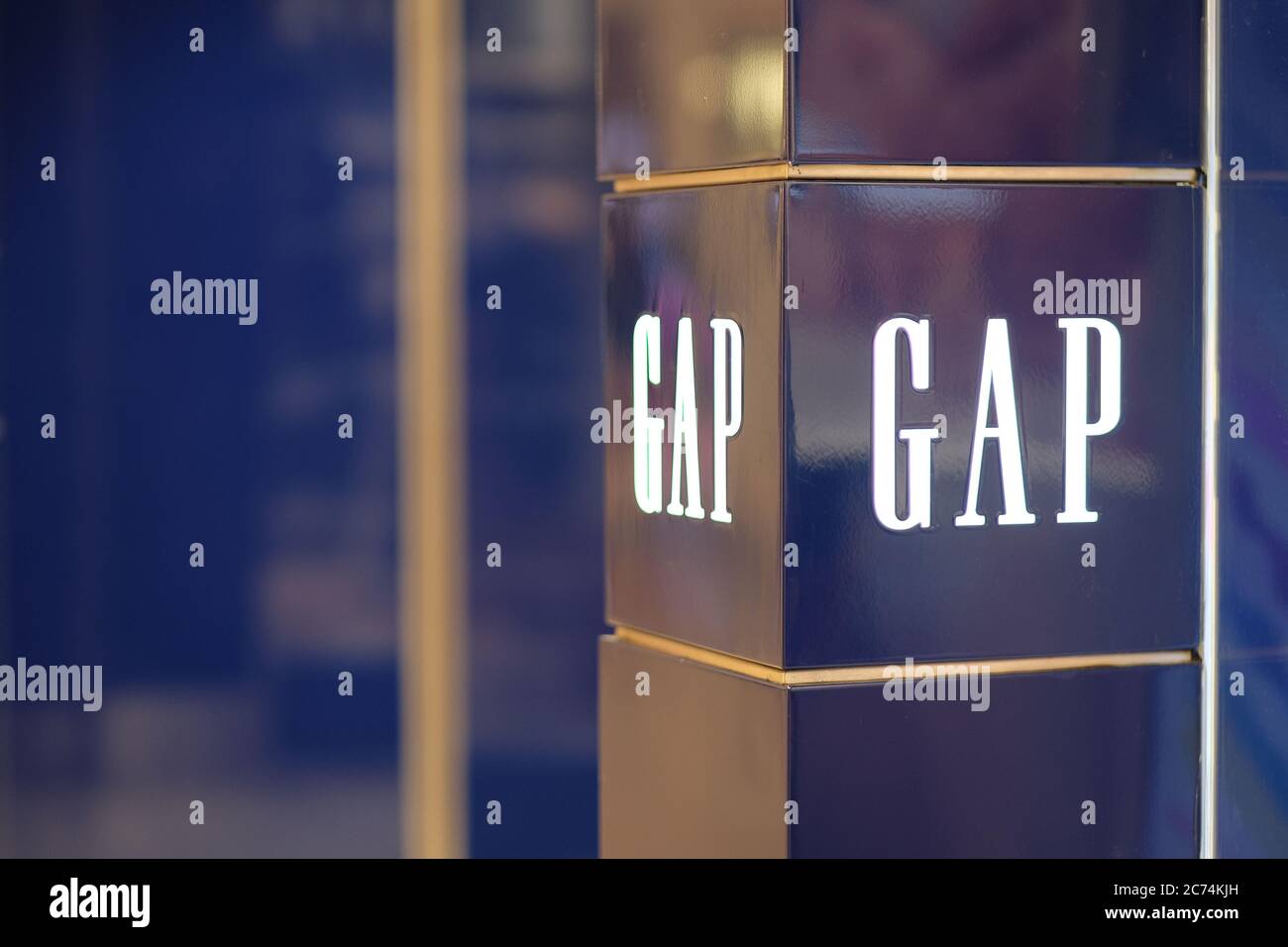 Close up bright white GAP logo on blue exterior wall of store. Blur ...