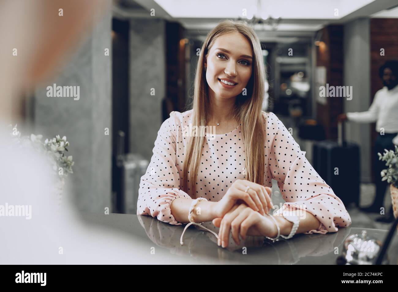 Blonde woman hotel guest checking-in at front desk in hotel Stock Photo ...