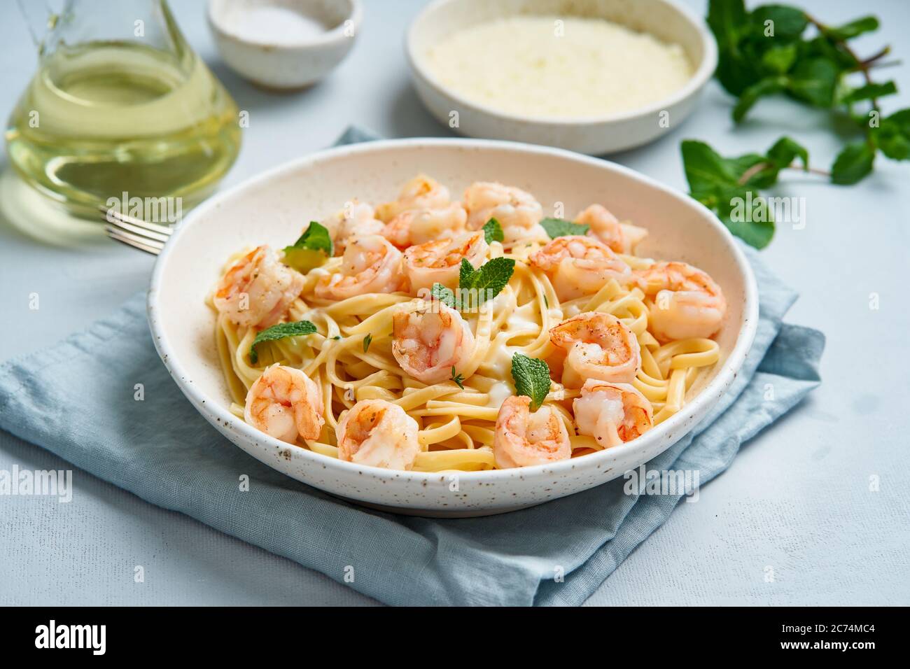 Pasta spaghetti with grilled shrimps, bechamel sauce, mint leaf on blue table Stock Photo - Alamy
