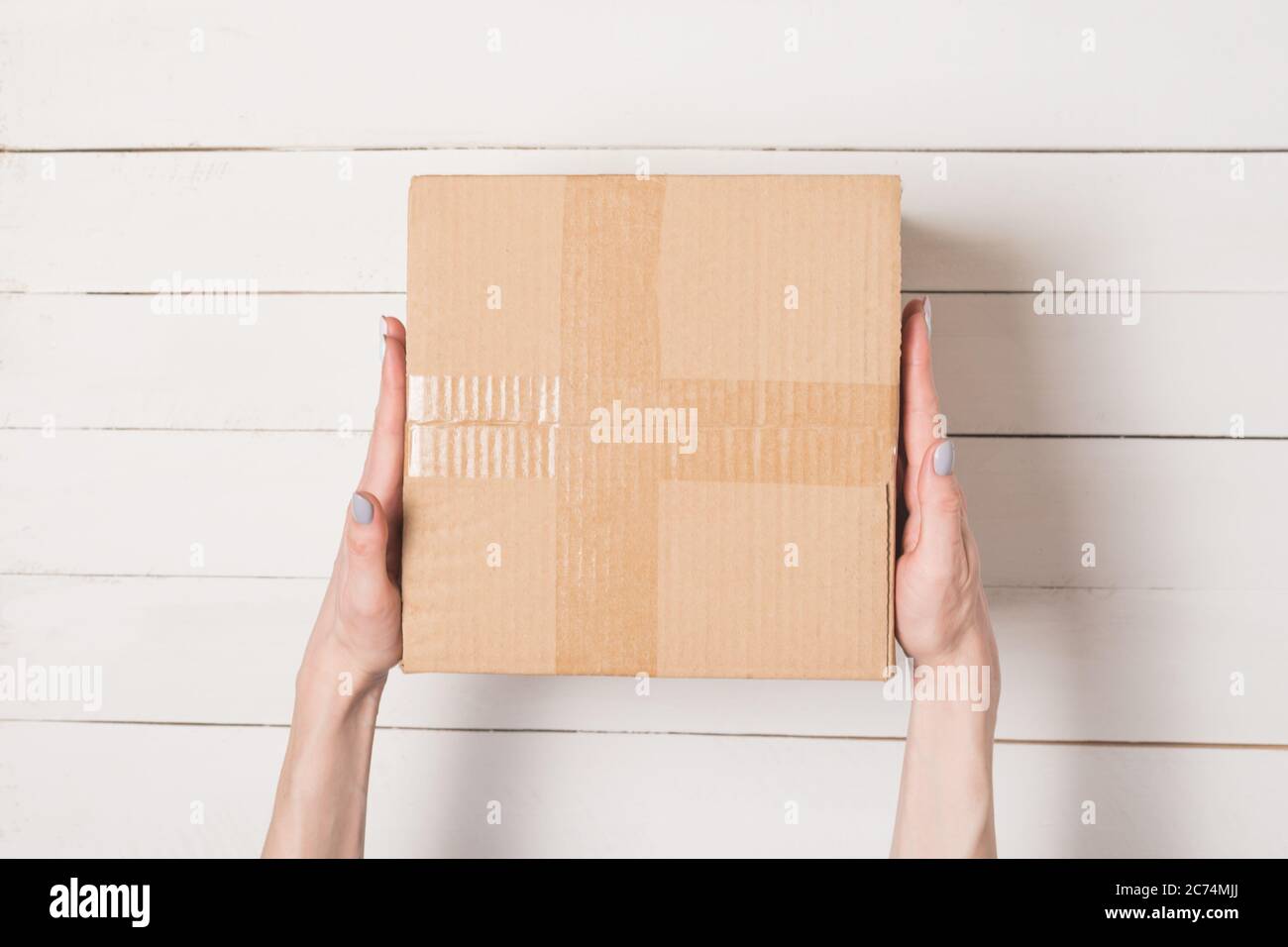 Parcel in female hands. Top view. White table on the background Stock ...