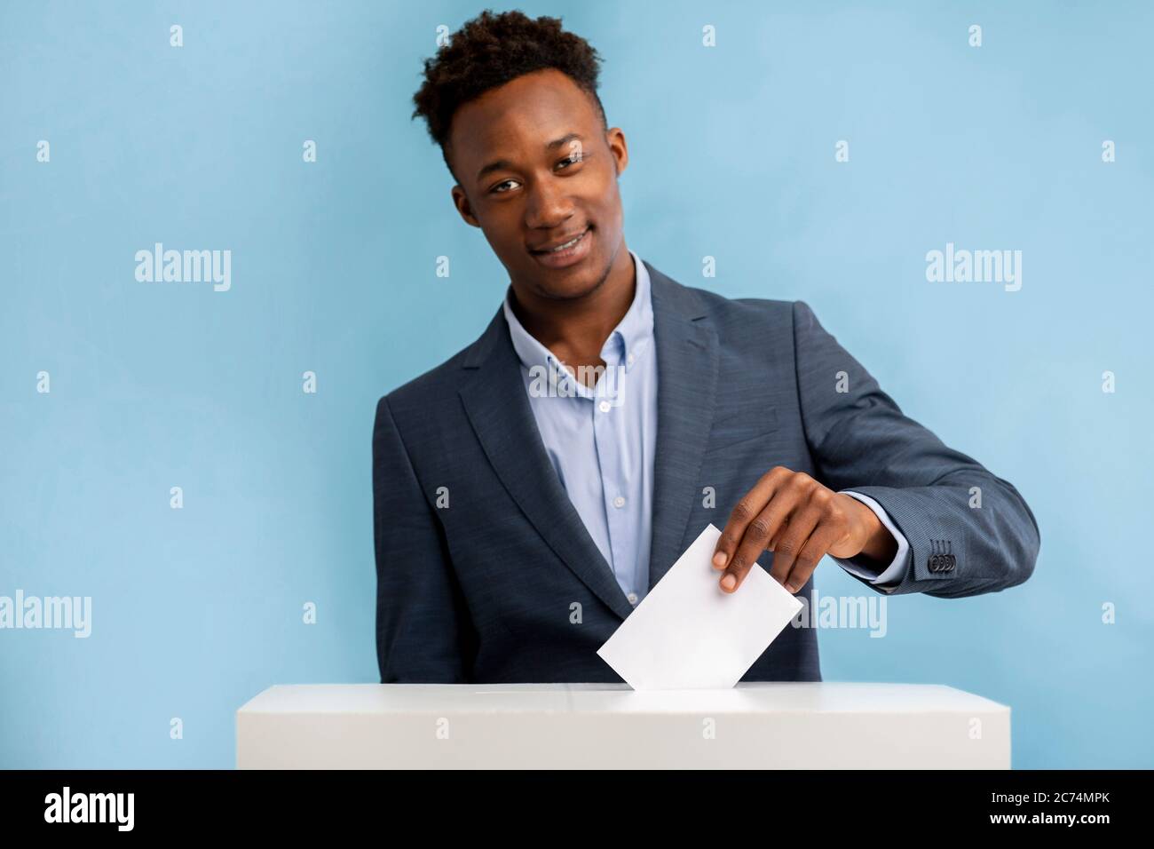 African voter pulls vote ballot. Blue background Stock Photo - Alamy