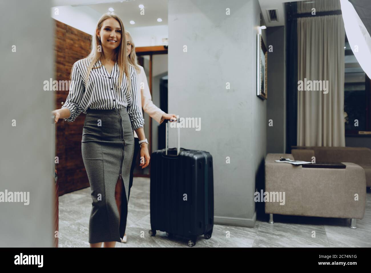 Two young women in formal clothes entering hotel lobby Stock Photo - Alamy