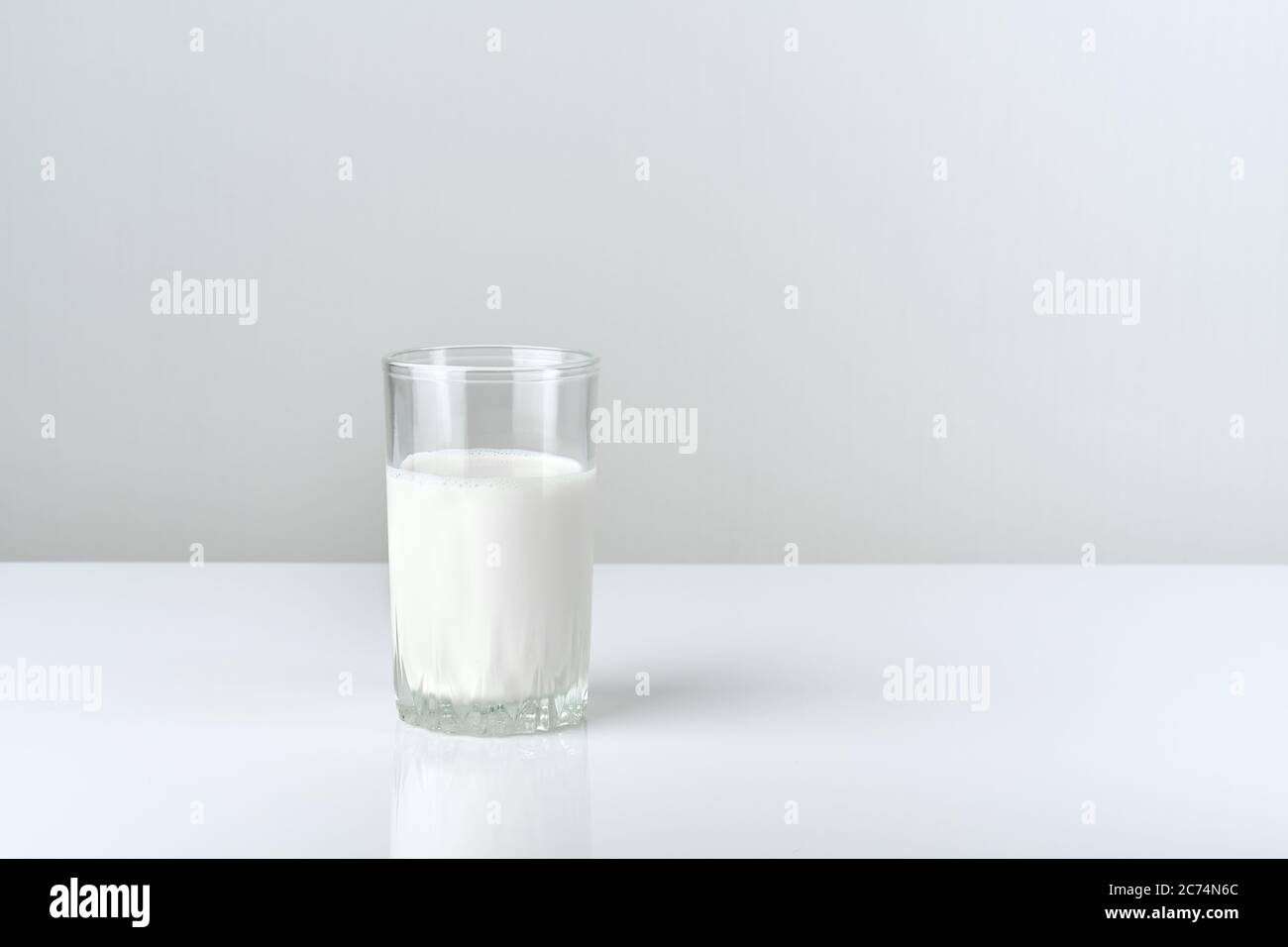 Glass of milk on white table on gray background, side view Stock Photo ...