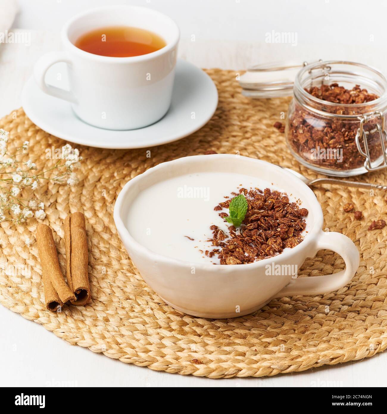 Yogurt with chocolate granola in cup, breakfast with tea on beige ...