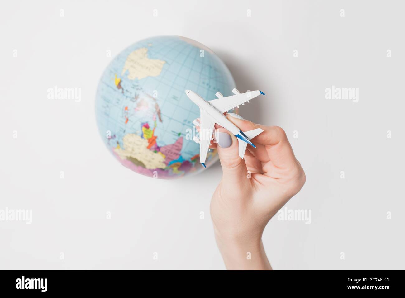 Passenger plane in a female hand on the background of the globe. Flight ...