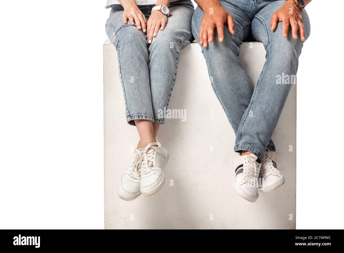 cropped view of couple in jeans sitting on cube isolated on white Stock ...