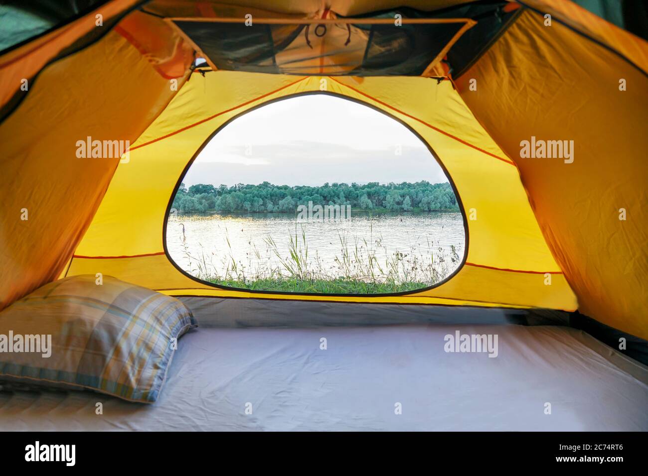 A tent with an open window stands on the banks of the river. From the ...