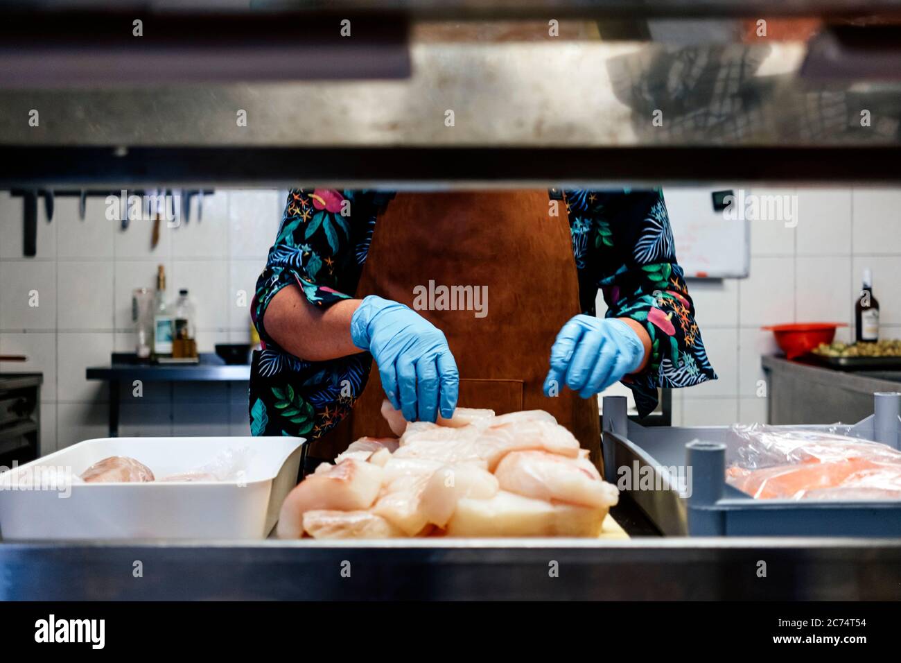 woman in restaurant kitchen cutting and preparing slices of fish Stock ...