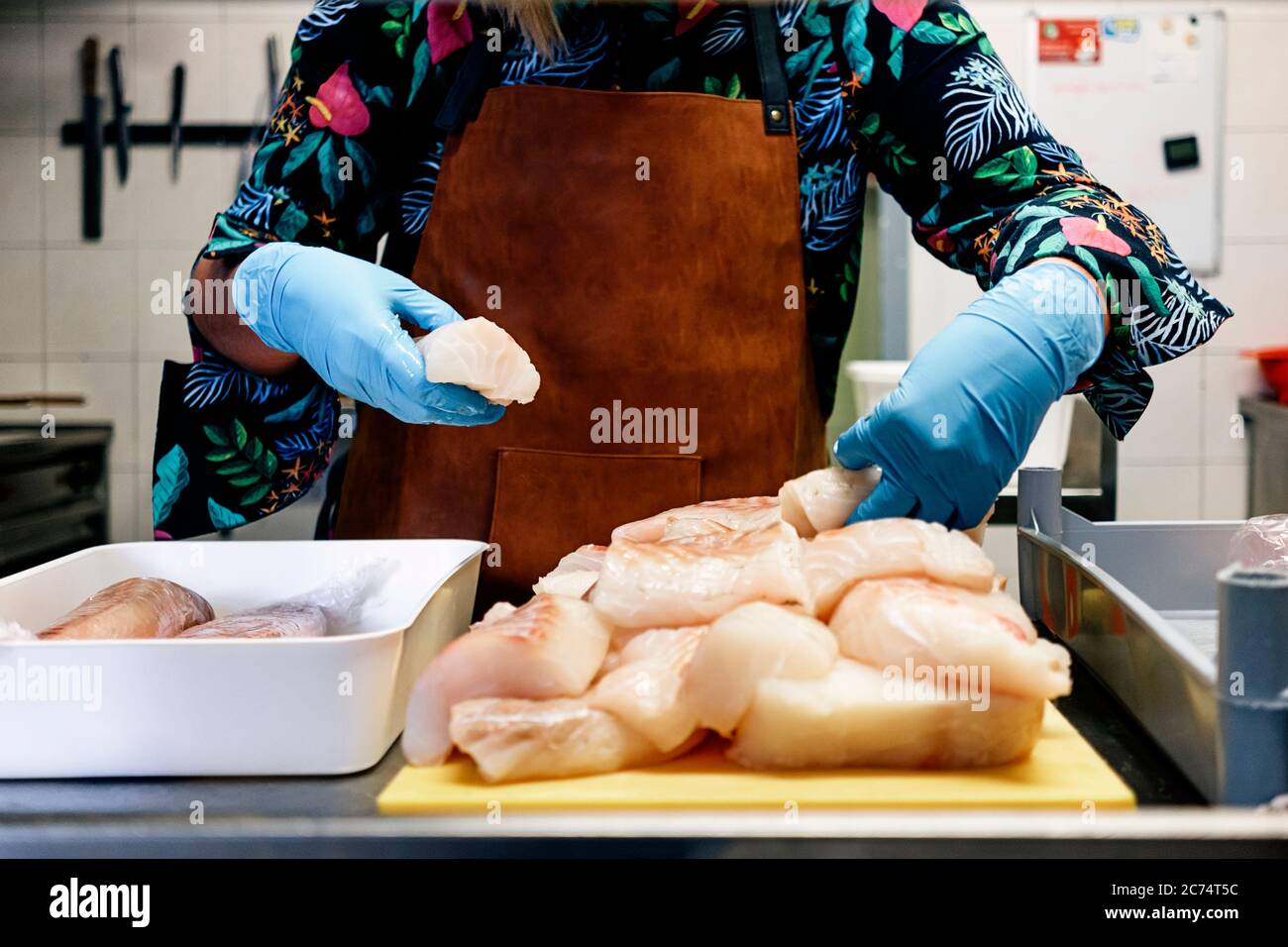 woman in restaurant kitchen cutting and preparing slices of fish Stock ...