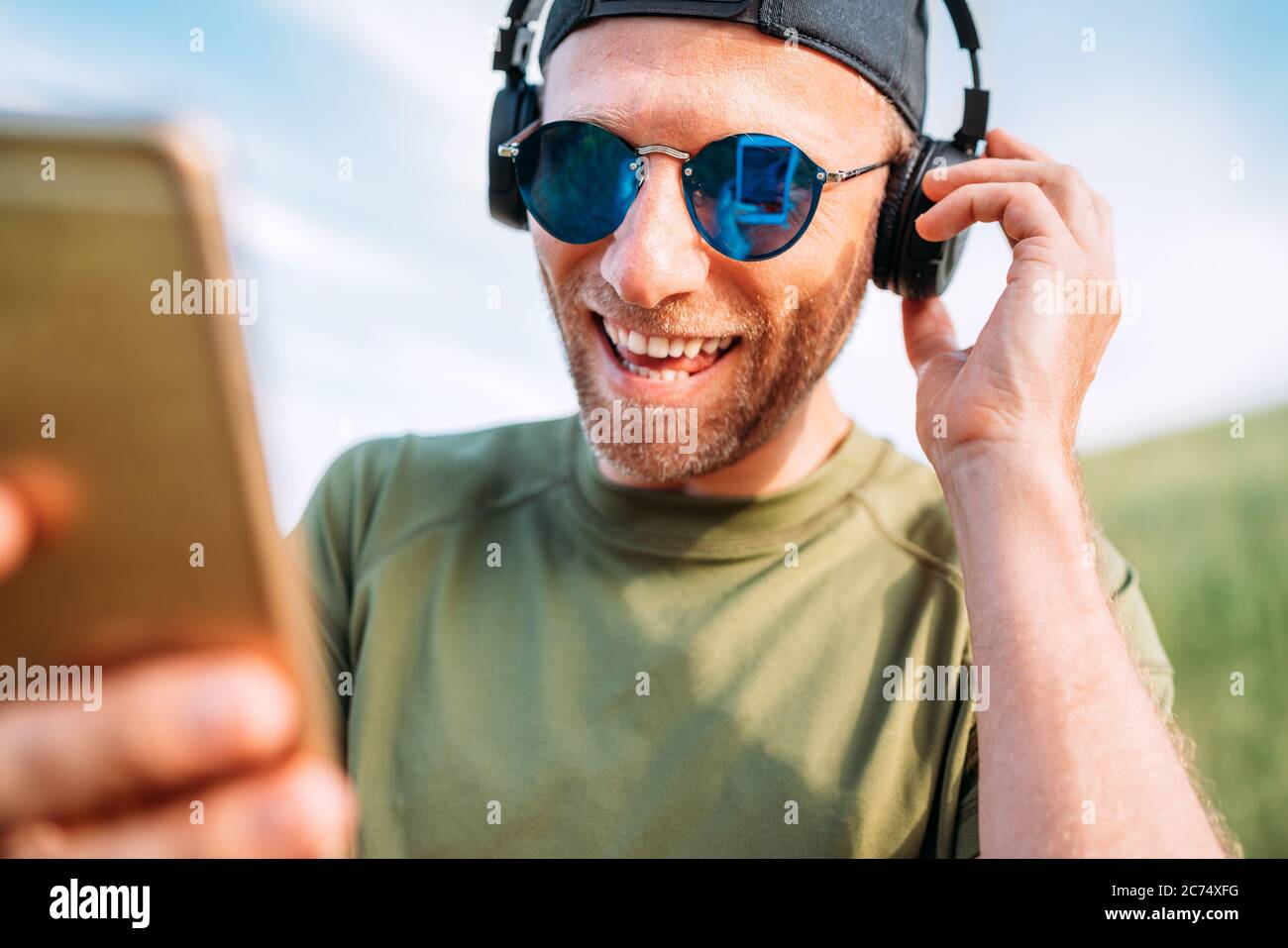 Cool man in baseball cap, wireless headphones and blue sunglasses ...