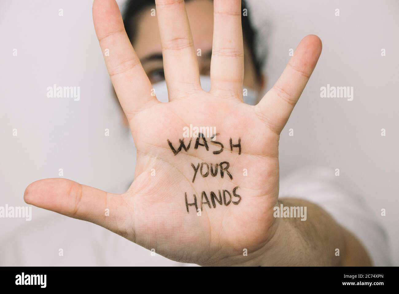 Woman wearing a safety mask with hand opened with the sentence "wash ...
