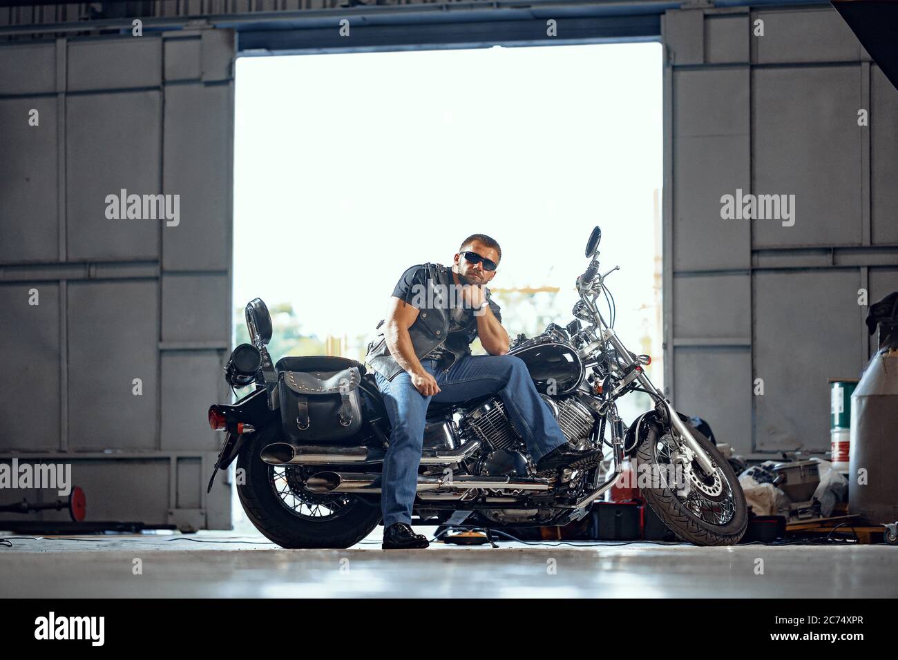 Bearded motorcyclist in black leather clothing with his motorbike Stock ...