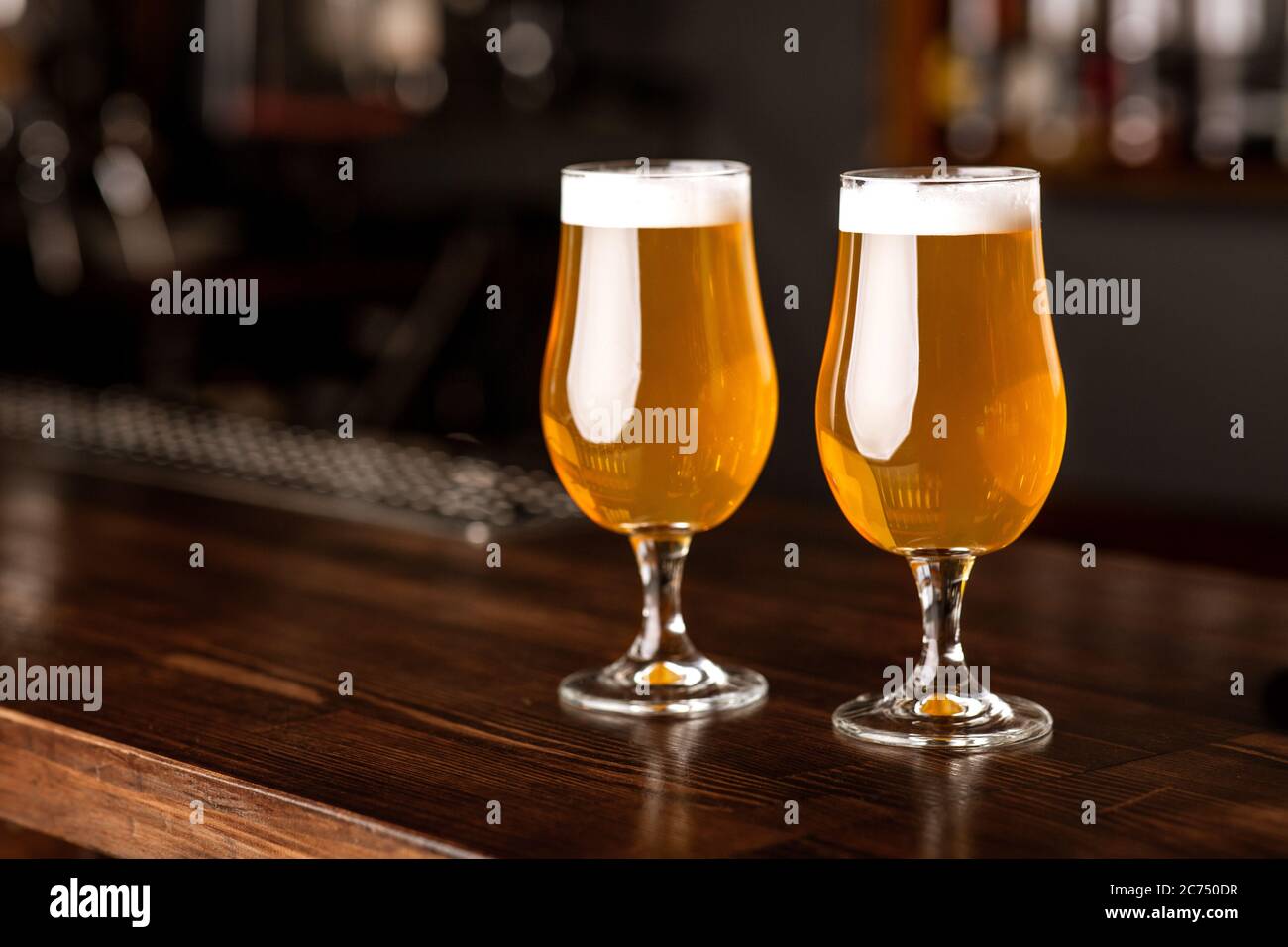 Date at pub. Glasses with light beer and foam on wooden bar counter in ...