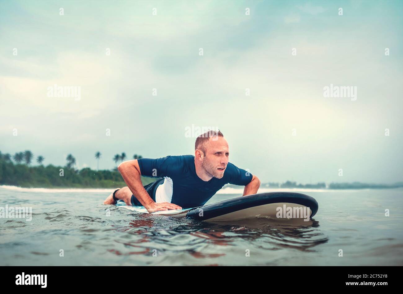 Man padding to line up on the surf board. Active holidays spending ...