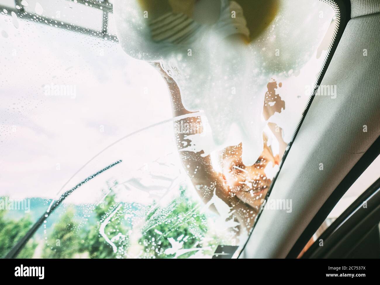 Little Boy washing his father windshield car window with soap foamy ...