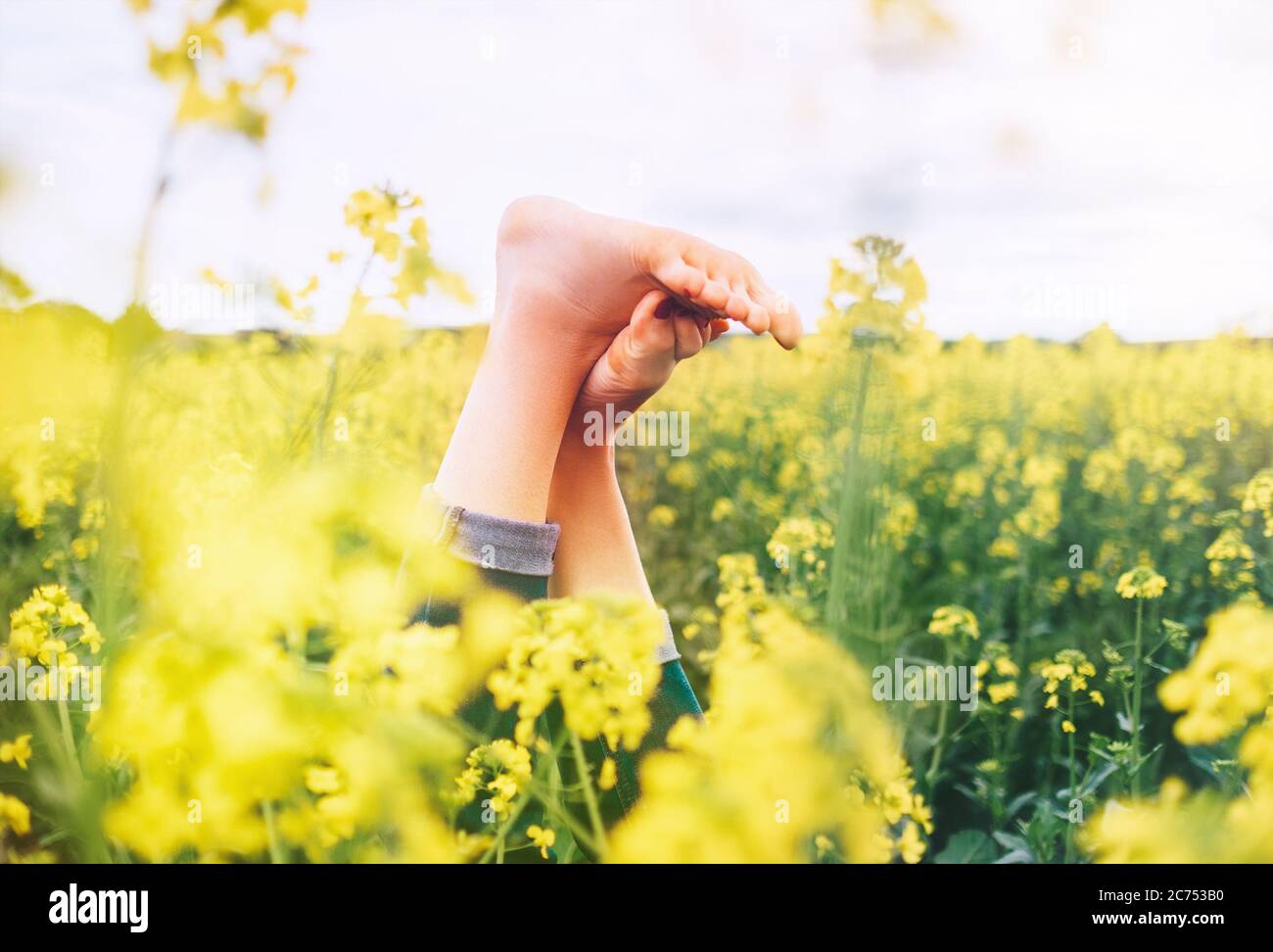 Legs up of happy female lying in deep yellow flowers meadow. Happiness ...