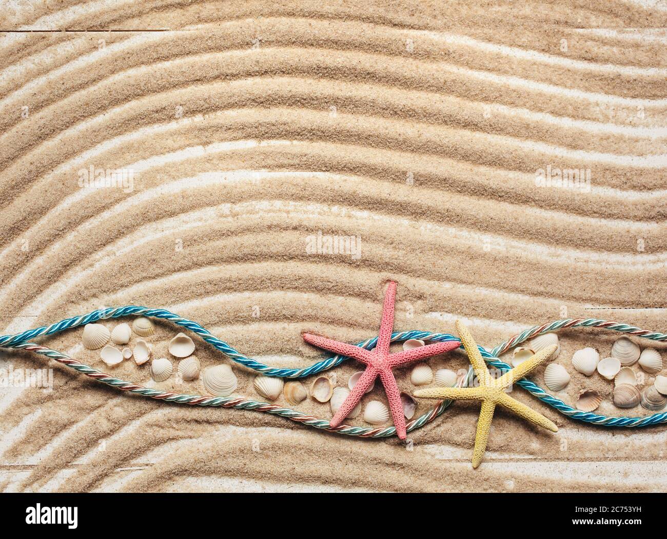 Starfish and colored ropes on a background of wavy sand. Marine cruise ...