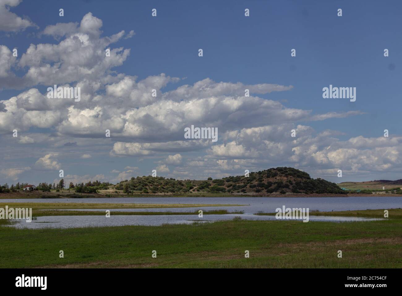 African landscape with a dam and hills behind the dam under blue sky ...