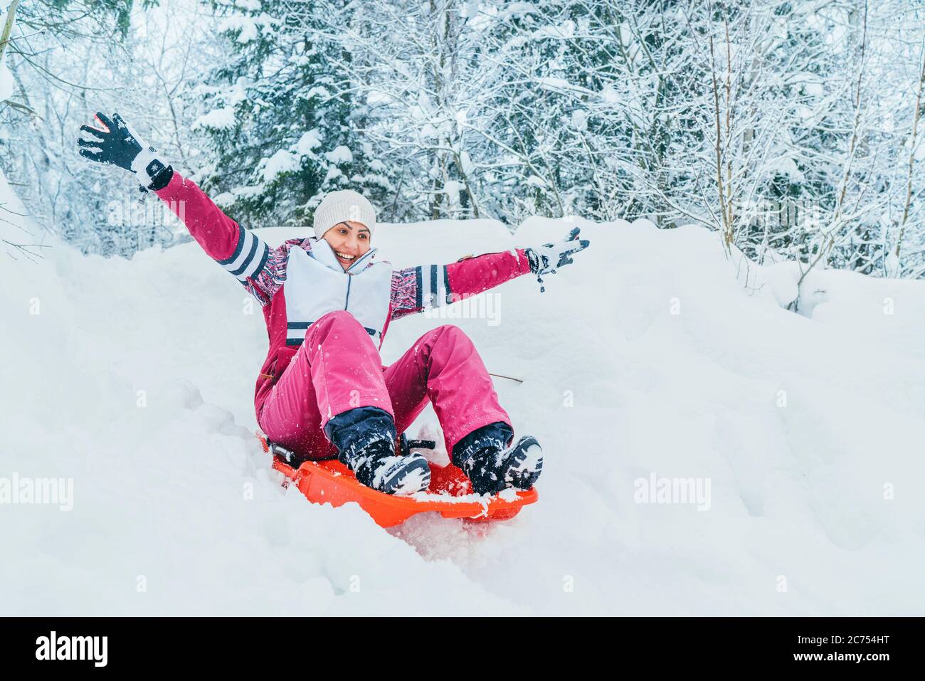 Young woman slide down from snow slope sitting in one slide.Winter ...