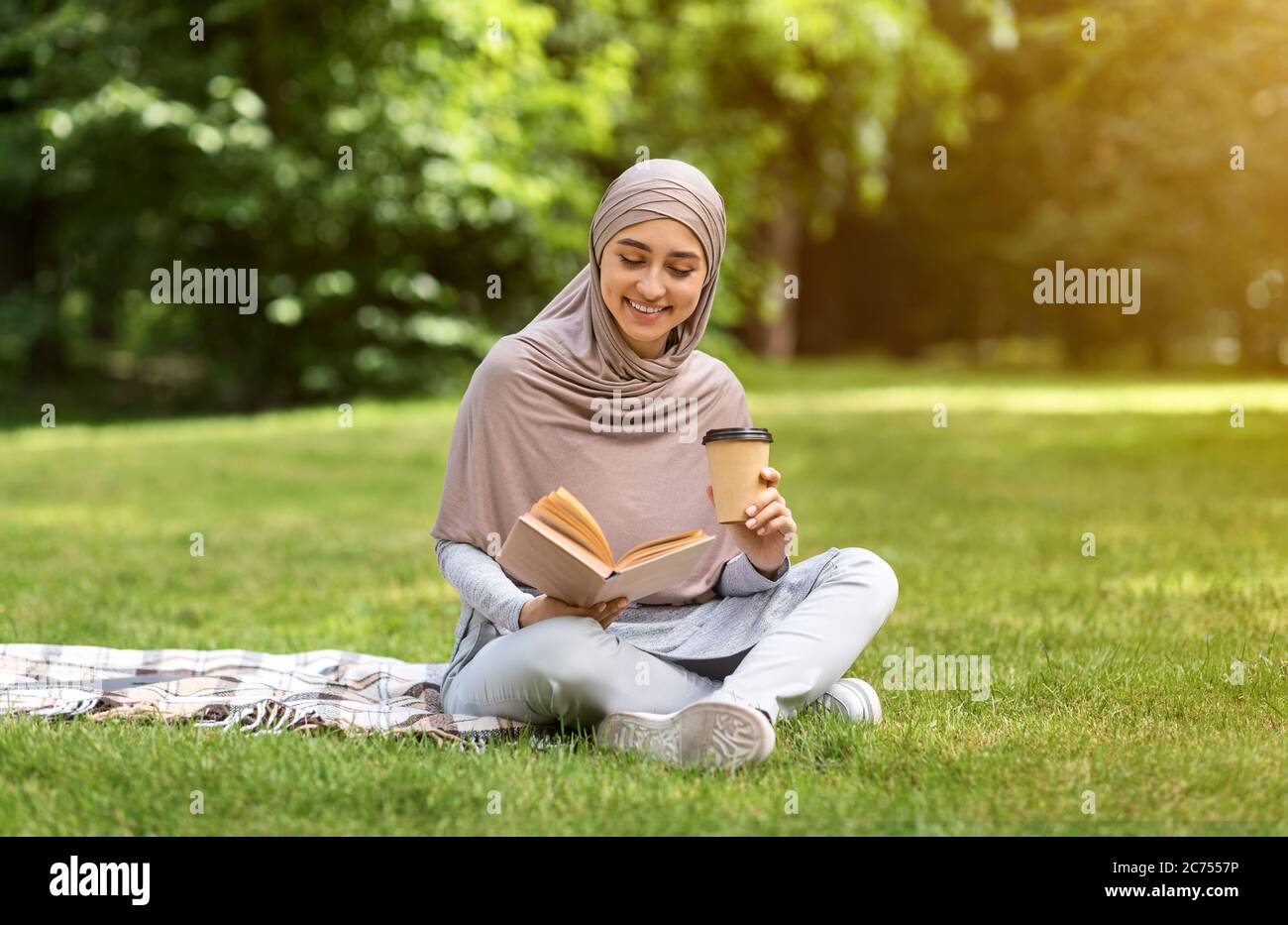 Pretty arab girl reading book at park Stock Photo - Alamy