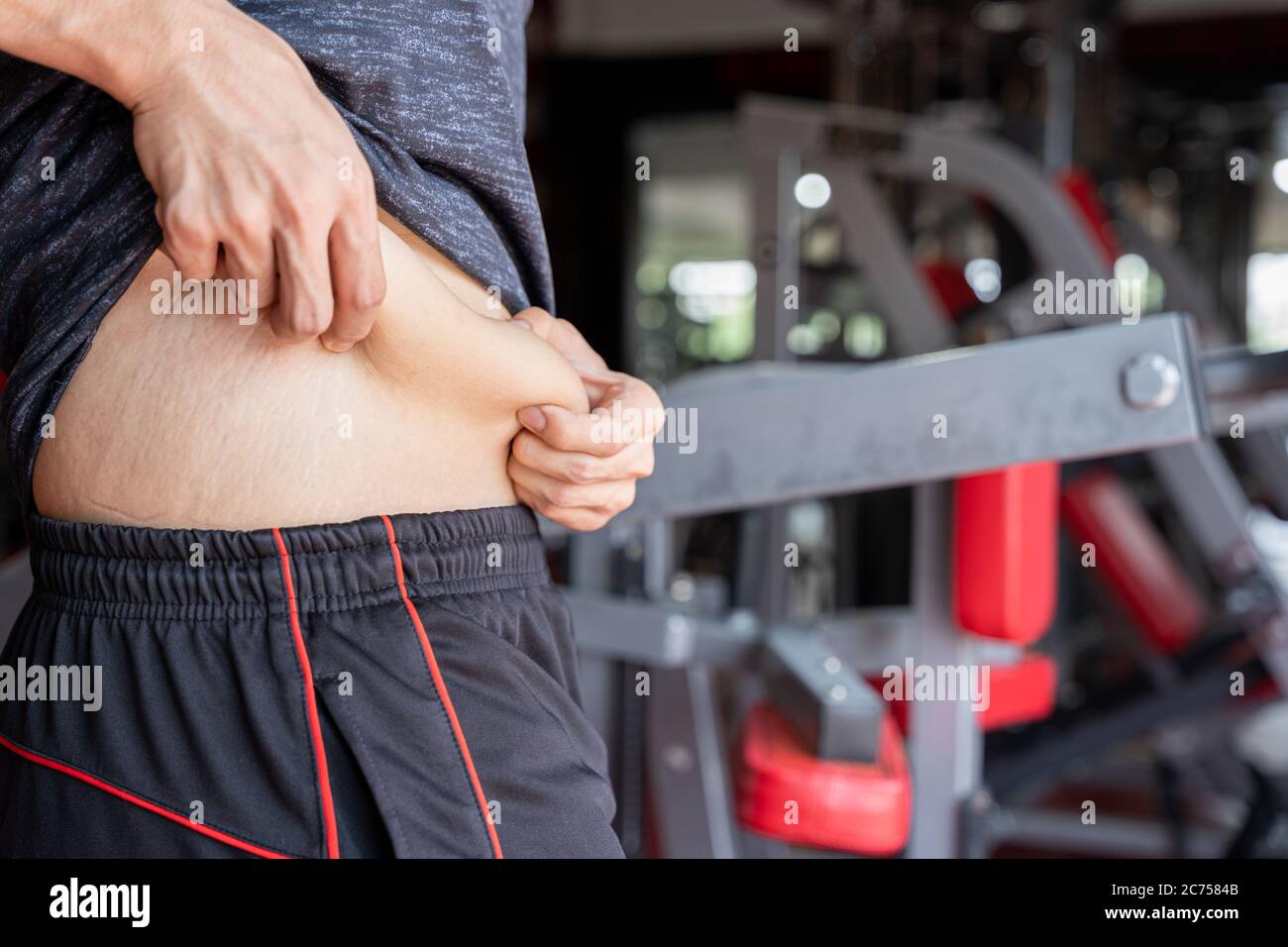 Fat man holding excessive fat belly, overweight fatty belly at fitness ...