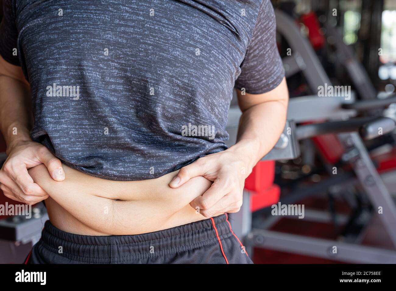 Fat man holding excessive fat belly, overweight fatty belly at fitness ...