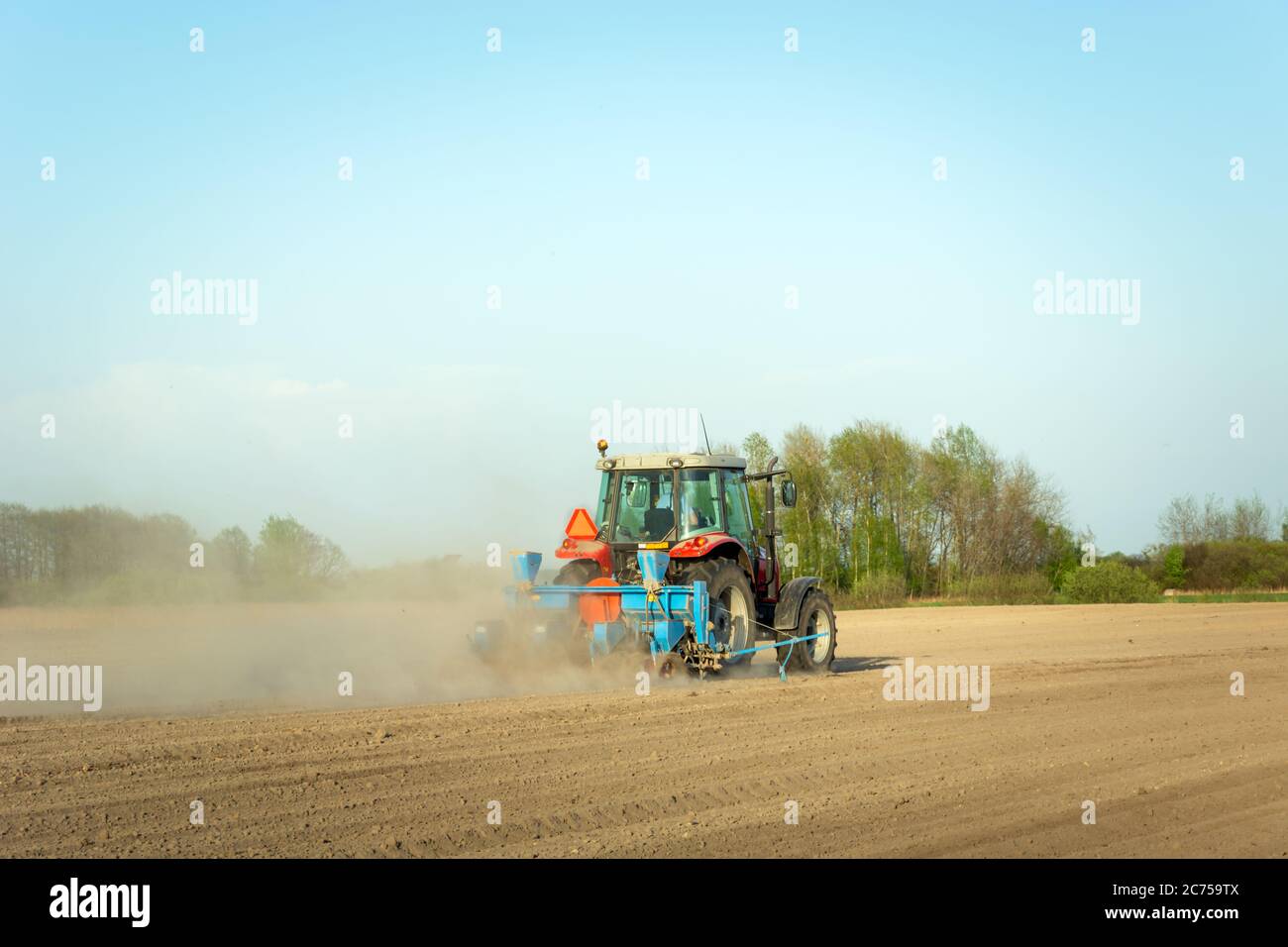 Tractor ploughing the field, dust from dry soil, spring agricultural ...