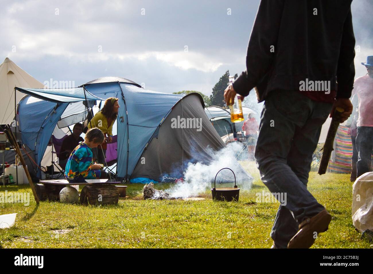 Preparing to cook on a campfire at a festival campsite with dark storm ...