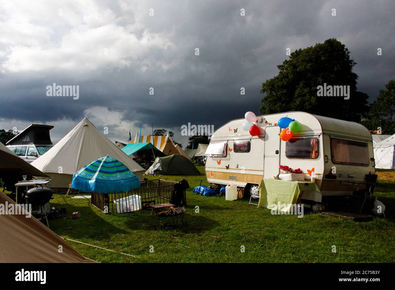 Camping field with tents and retro caravan at a festival campsite with ...