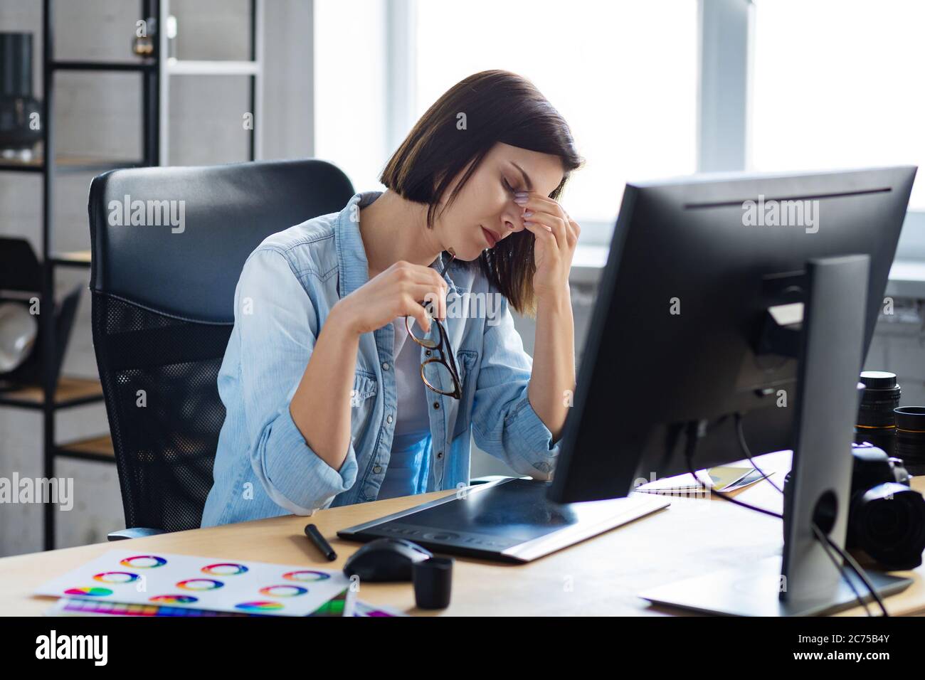 Portrait of tired graphic designer working overtime in office. Stressed ...