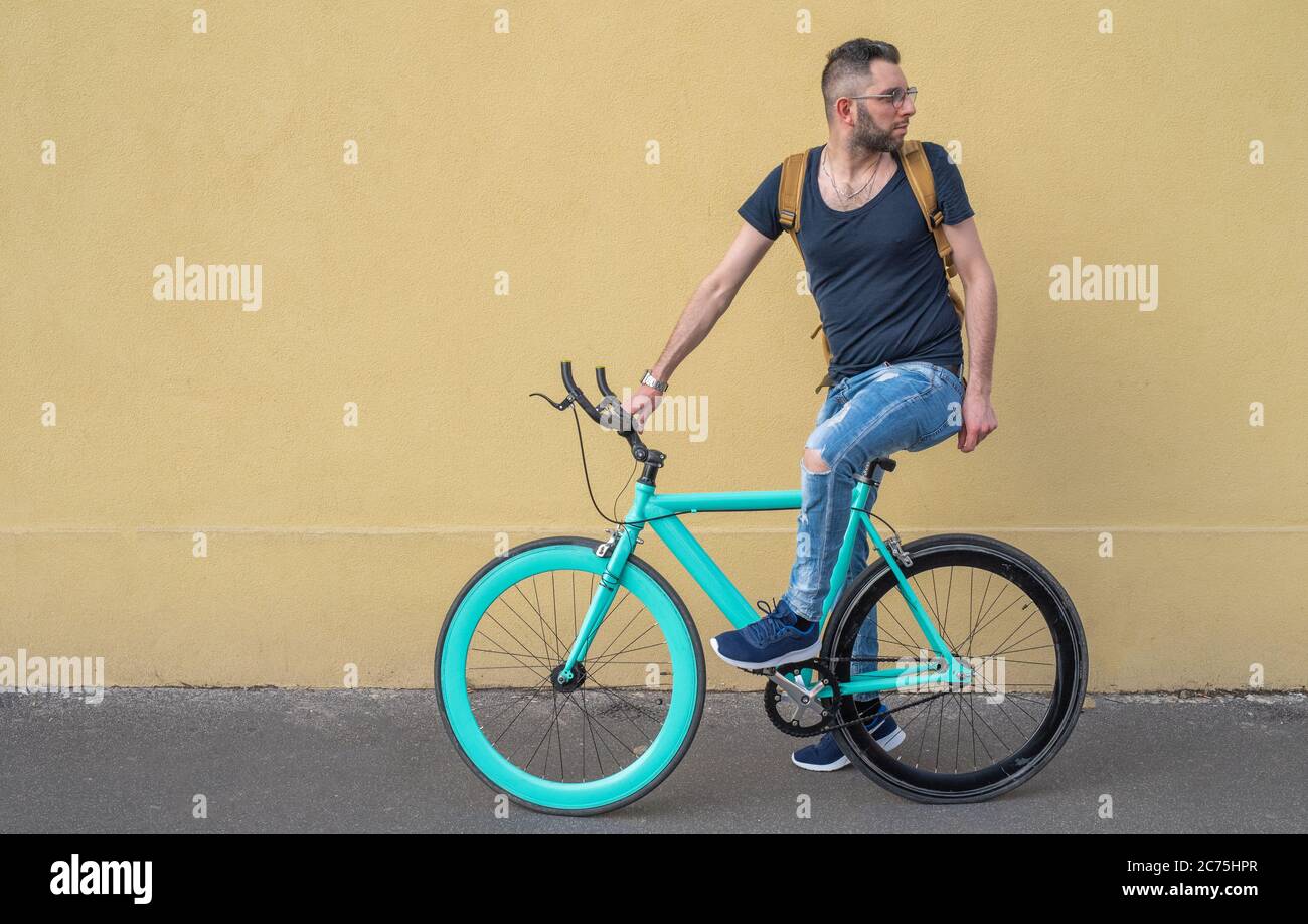 trendy young man posing on a minimalist bicycle, portrait of fashion ...