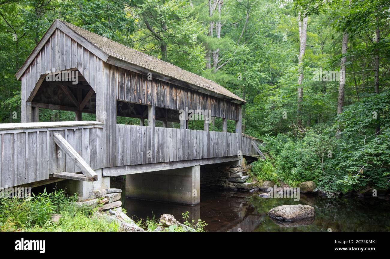 Wooden Covered bridge over a small river in a lush green forest at ...
