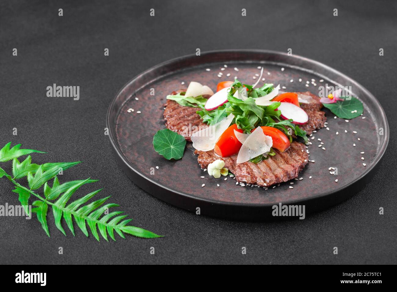 Hot appetizer thin slices of grilled beef with cherry tomatoes, arugula ...
