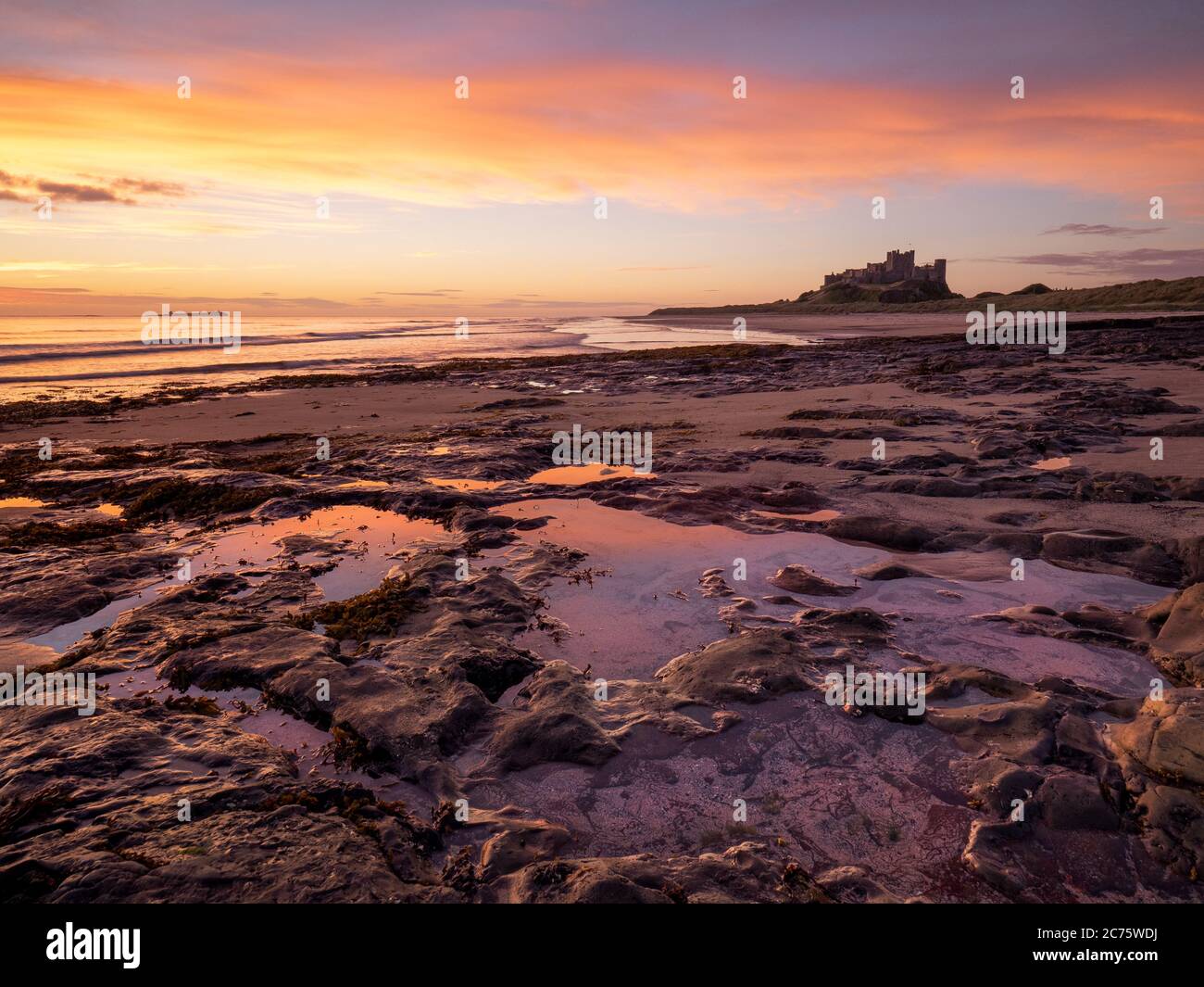 A vibrant sunrise is reflected in beautiful tidal pools on Bamburgh ...