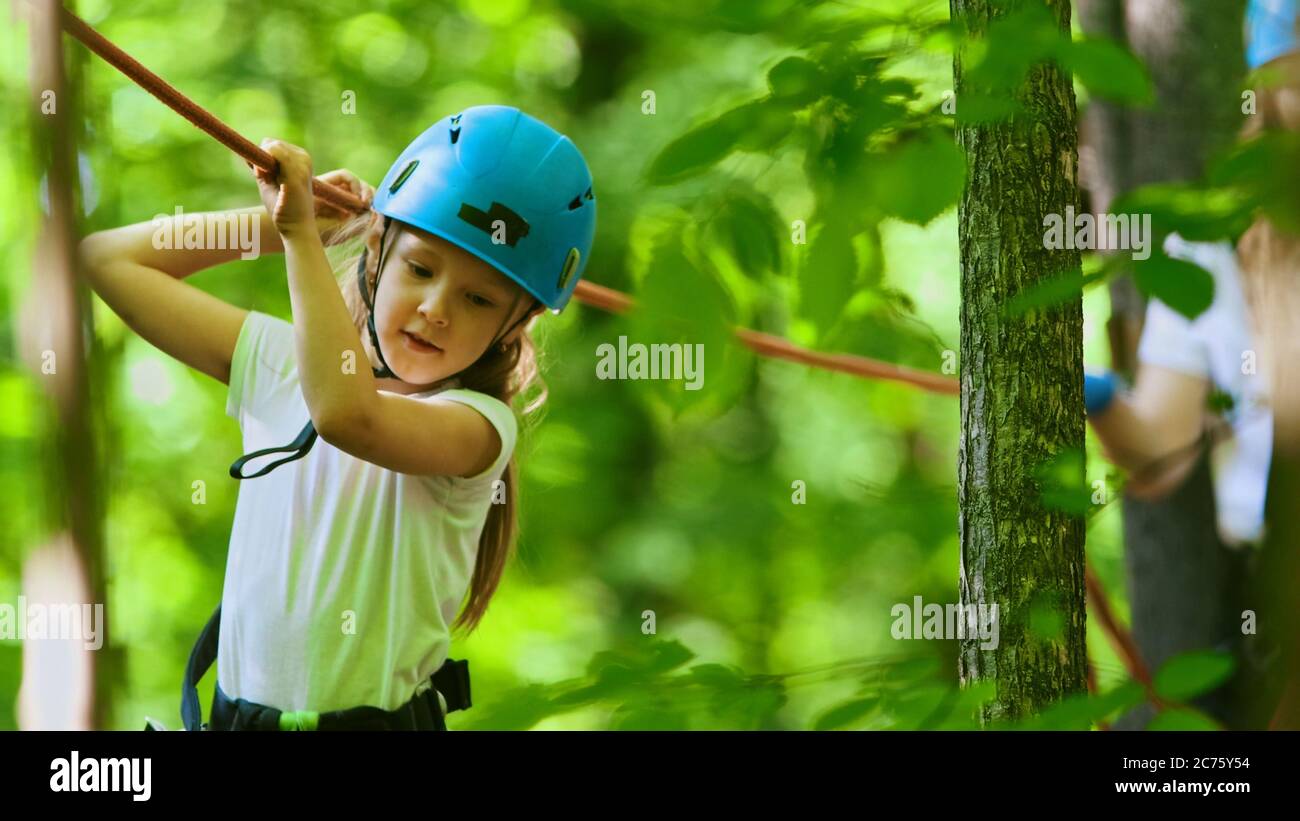 A little girl having a rope adventure in the forest. Mid shot Stock ...