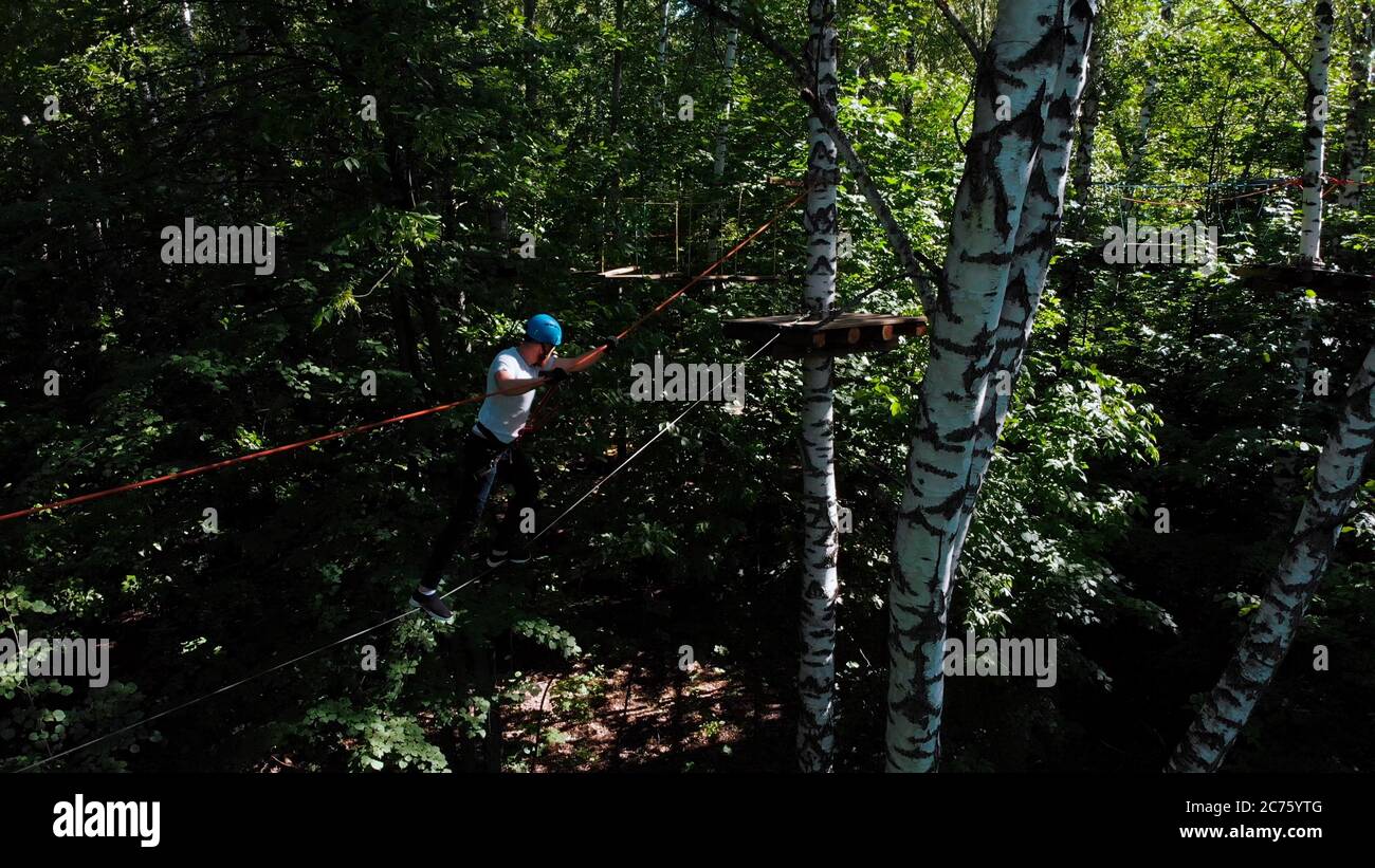Rope adventure - man walking on the rope between trees. Mid shot Stock ...