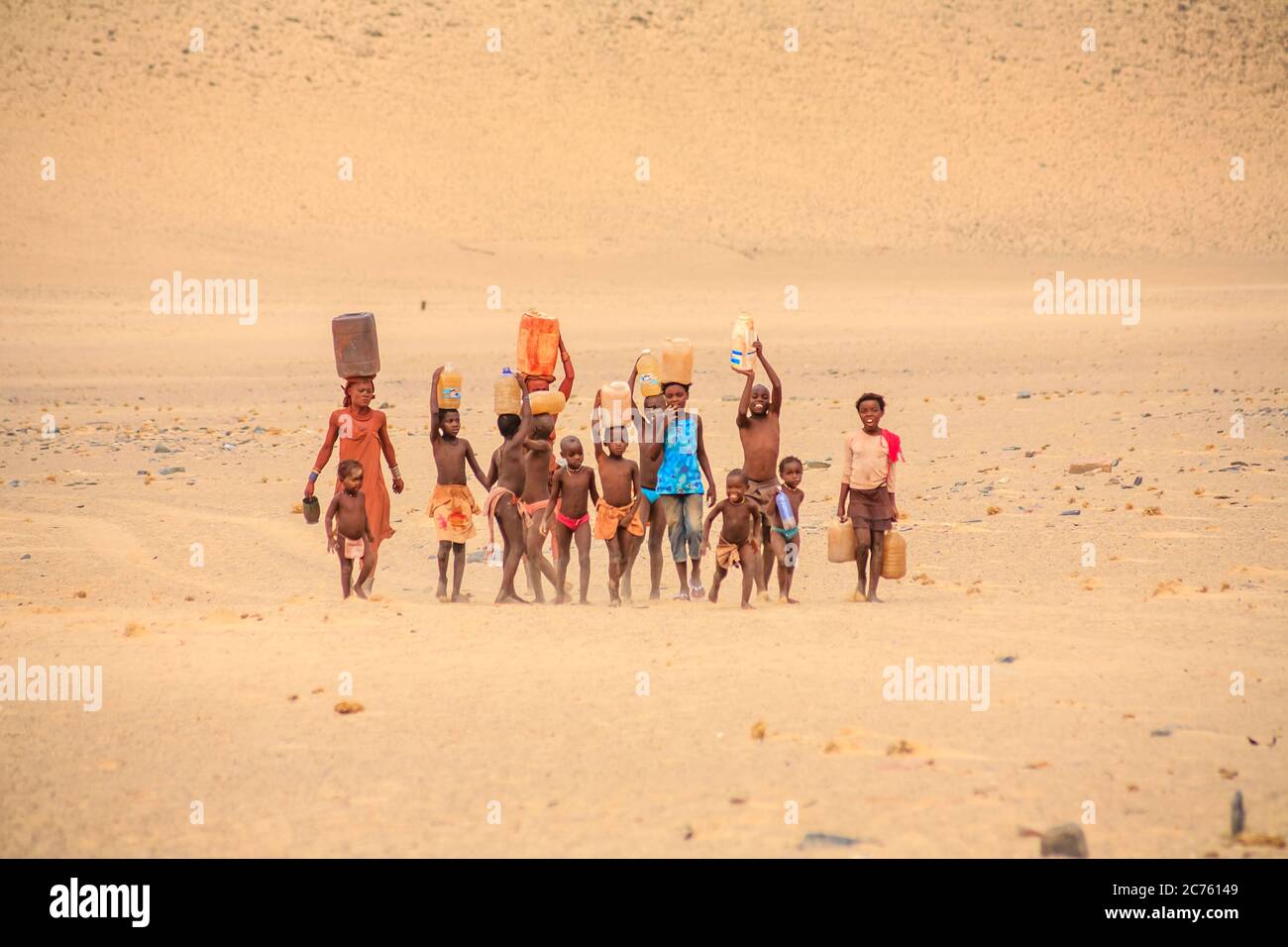 Himba woman and children working carrying water to a village of Himba ...