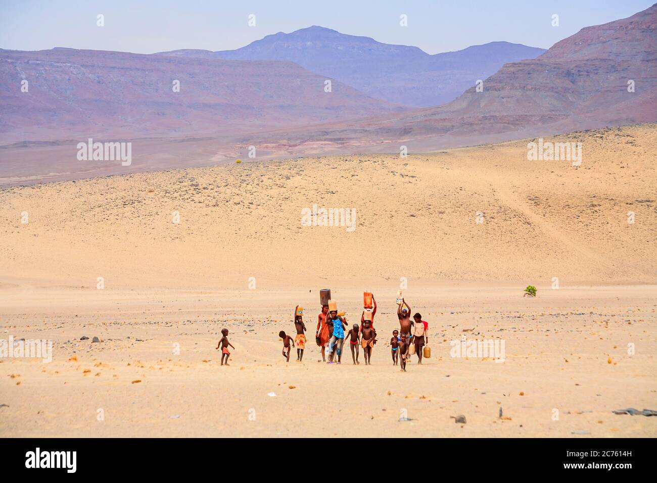 Himba woman and children working carrying water to a village of Himba ...