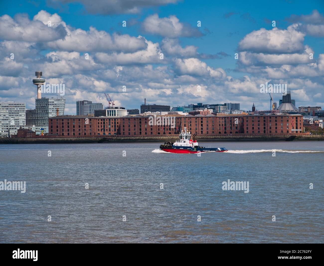 A tug boat passes the front of the Albert Dock warehouse buildings on ...