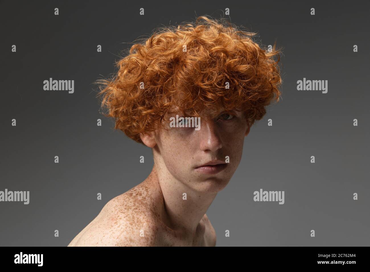 Lightning. Fashion portrait of beautiful redhead man isolated on grey ...