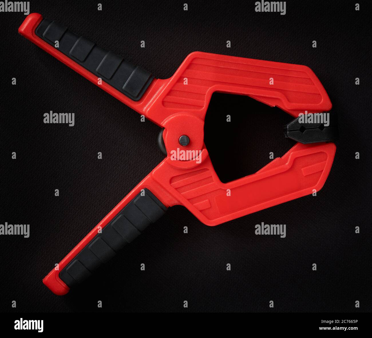 Red spring clamp on dark background. Plastic clamp. Clamping tools for ...