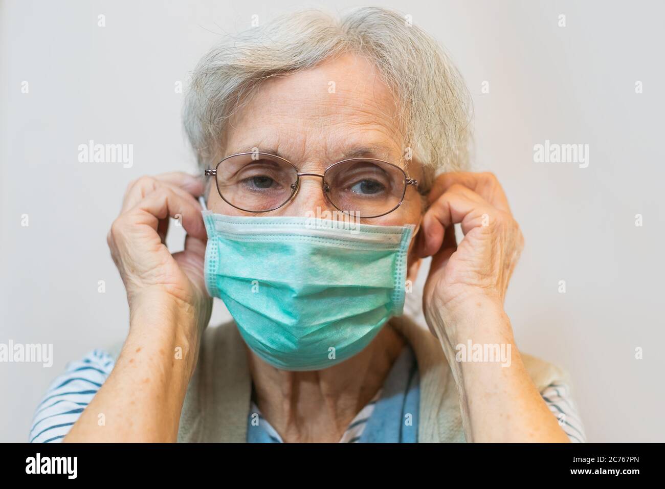 old woman putting on a face mask Stock Photo - Alamy