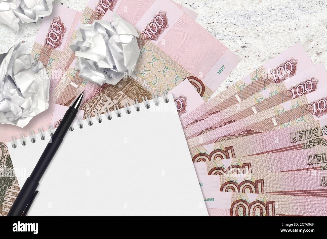 100 russian rubles bills and balls of crumpled paper with notepad. Bad ...
