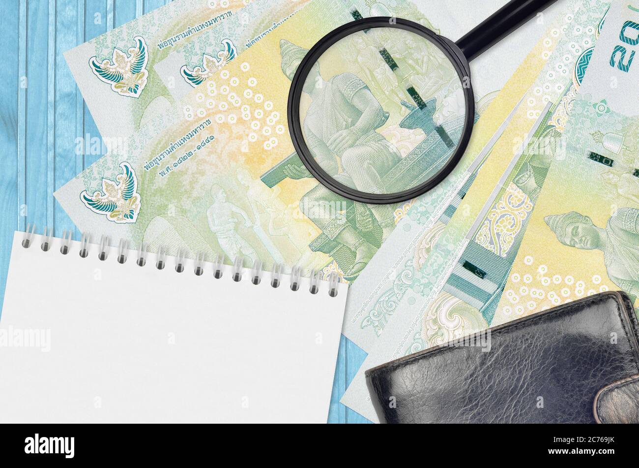 20 Thai Baht bills and magnifying glass with black purse and notepad ...