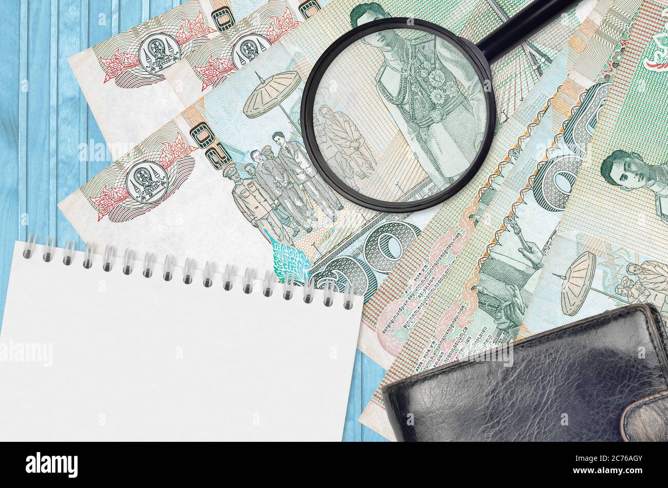 20 Thai Baht bills and magnifying glass with black purse and notepad ...