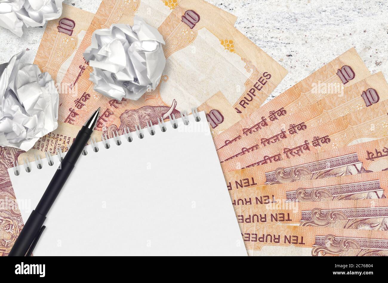10 Indian rupees bills and balls of crumpled paper with notepad. Bad ...