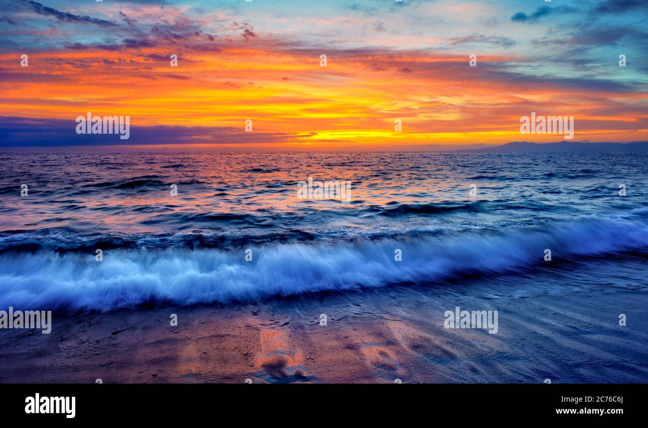 A Colorful Ocean Sunset Sky as a Gentle Wave Rolls to Shore Stock Photo ...